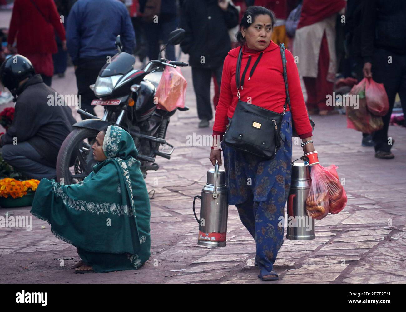 Kathmandu, Bagmati, Nepal. 8th Mar, 2023. A woman moves forward to sell tea and snacks carrying ...