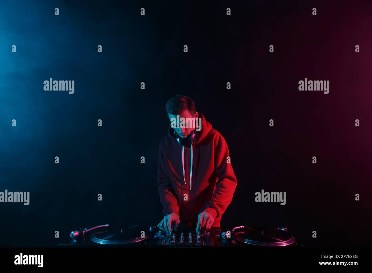 Club DJ mixing vinyl records with sound mixer on a party in night club ...
