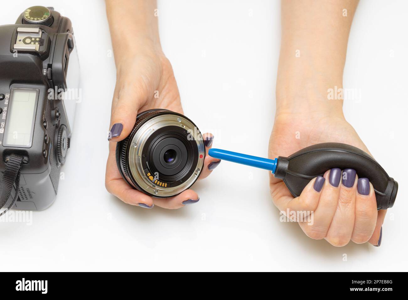 a man blows dust off a camera lens with a pear. man cleaning camera ...