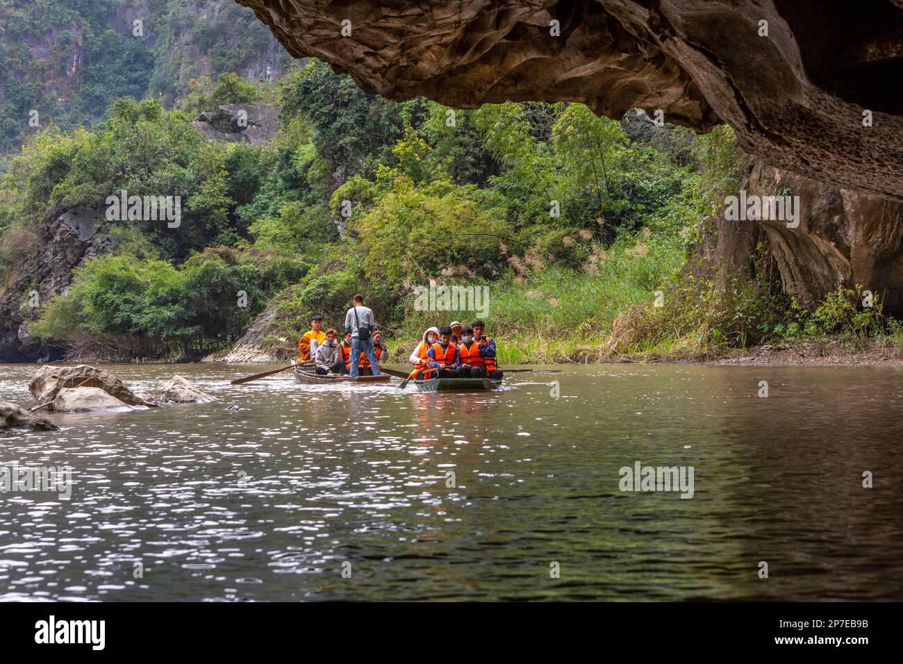 Tourist canoes entering a cave tunnel on a river in Ninh Binh, Vietnam ...
