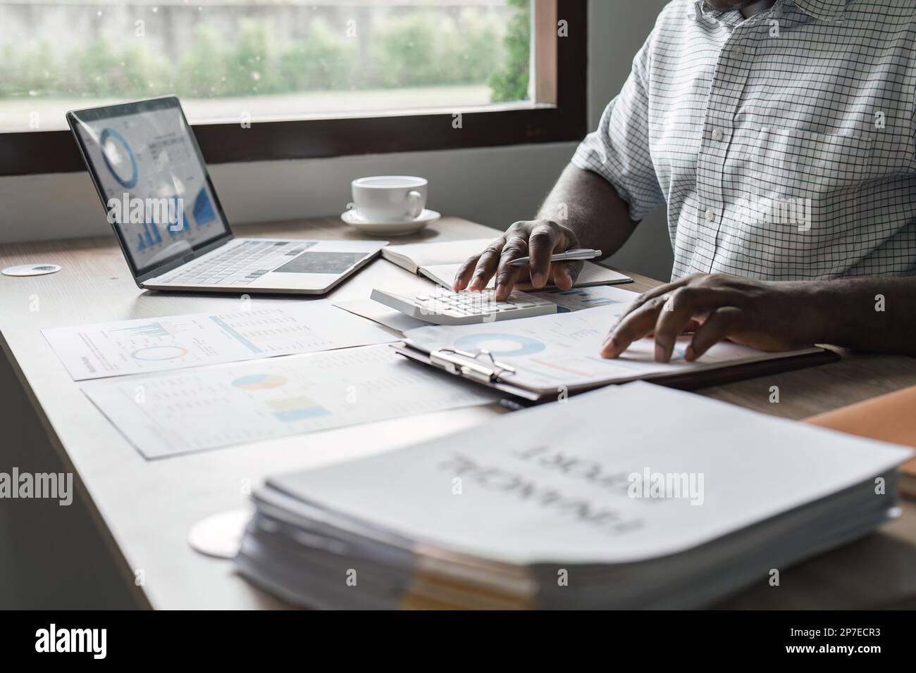 Happy black man planning budget, calculating expenses and taking notes ...