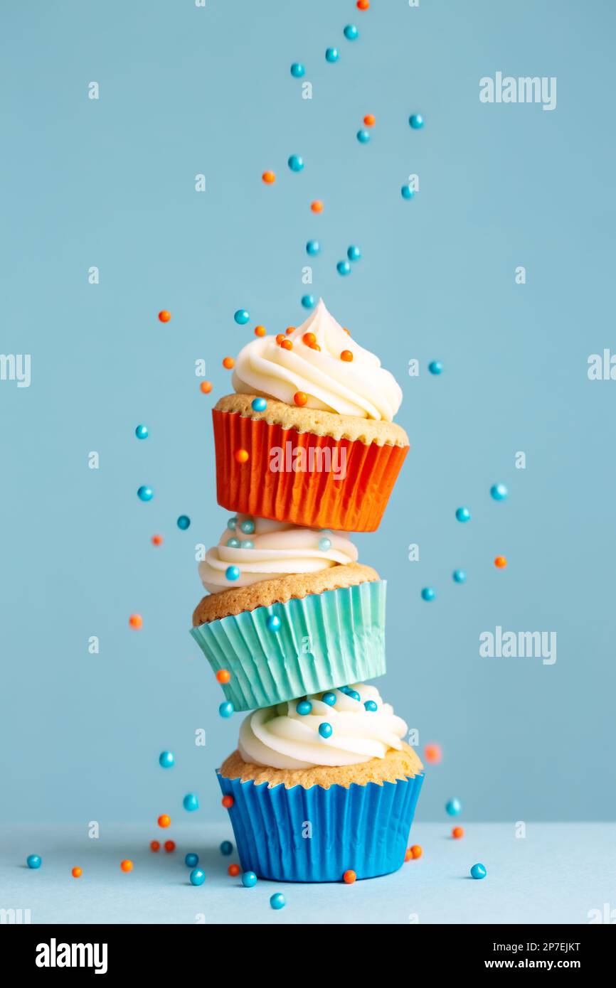 Sugar sprinkles falling on stack of colorful cupcakes Stock Photo - Alamy