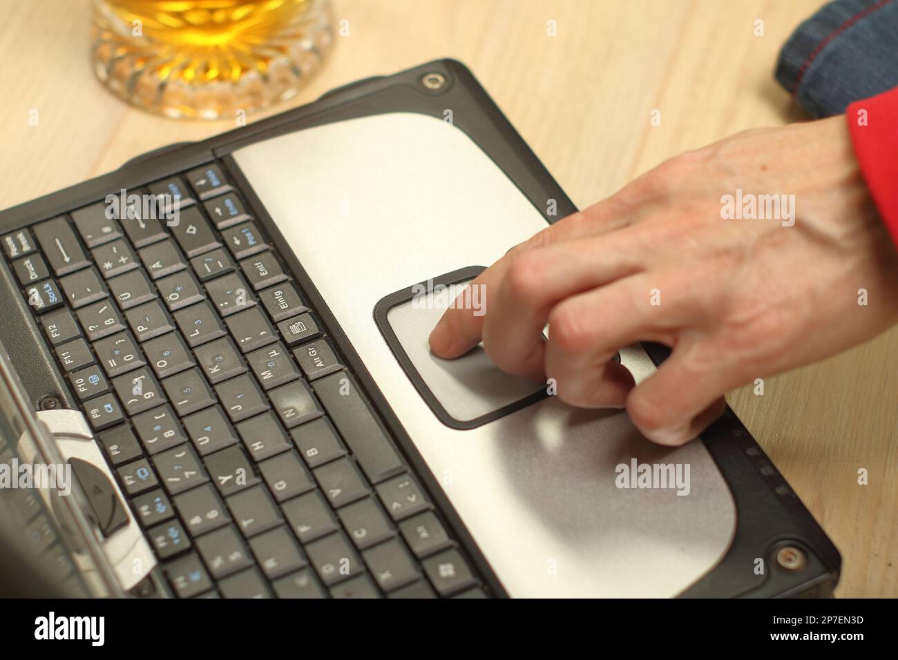 person typing on the keyboard of an old laptop next to a beer mug Stock ...