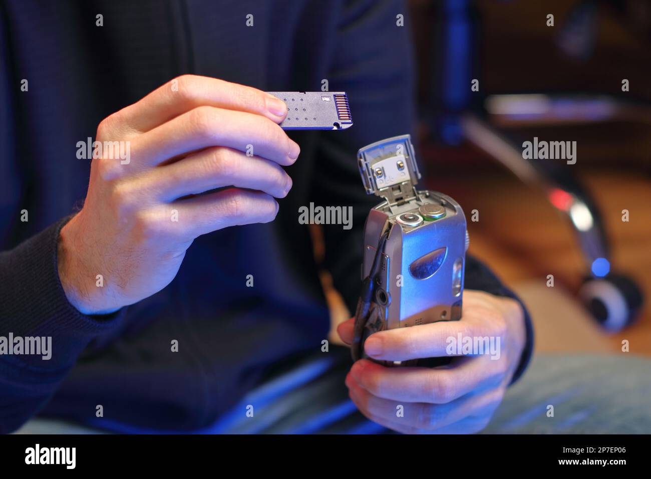 a person in the background taking out a memory card from an old compact ...