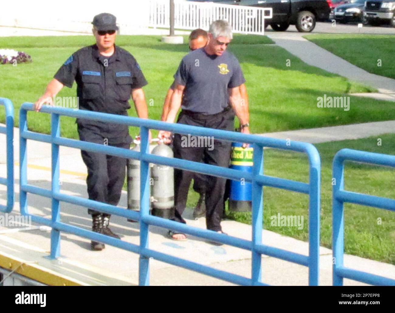 Members of the Michigan State Police dive team carry air tanks to a ...