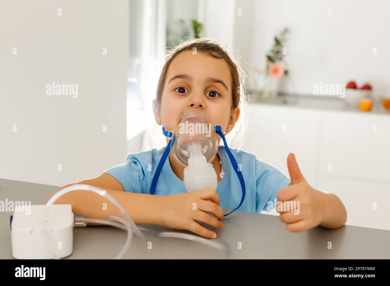 Little girl in a mask for inhalations, making inhalation with nebulizer ...