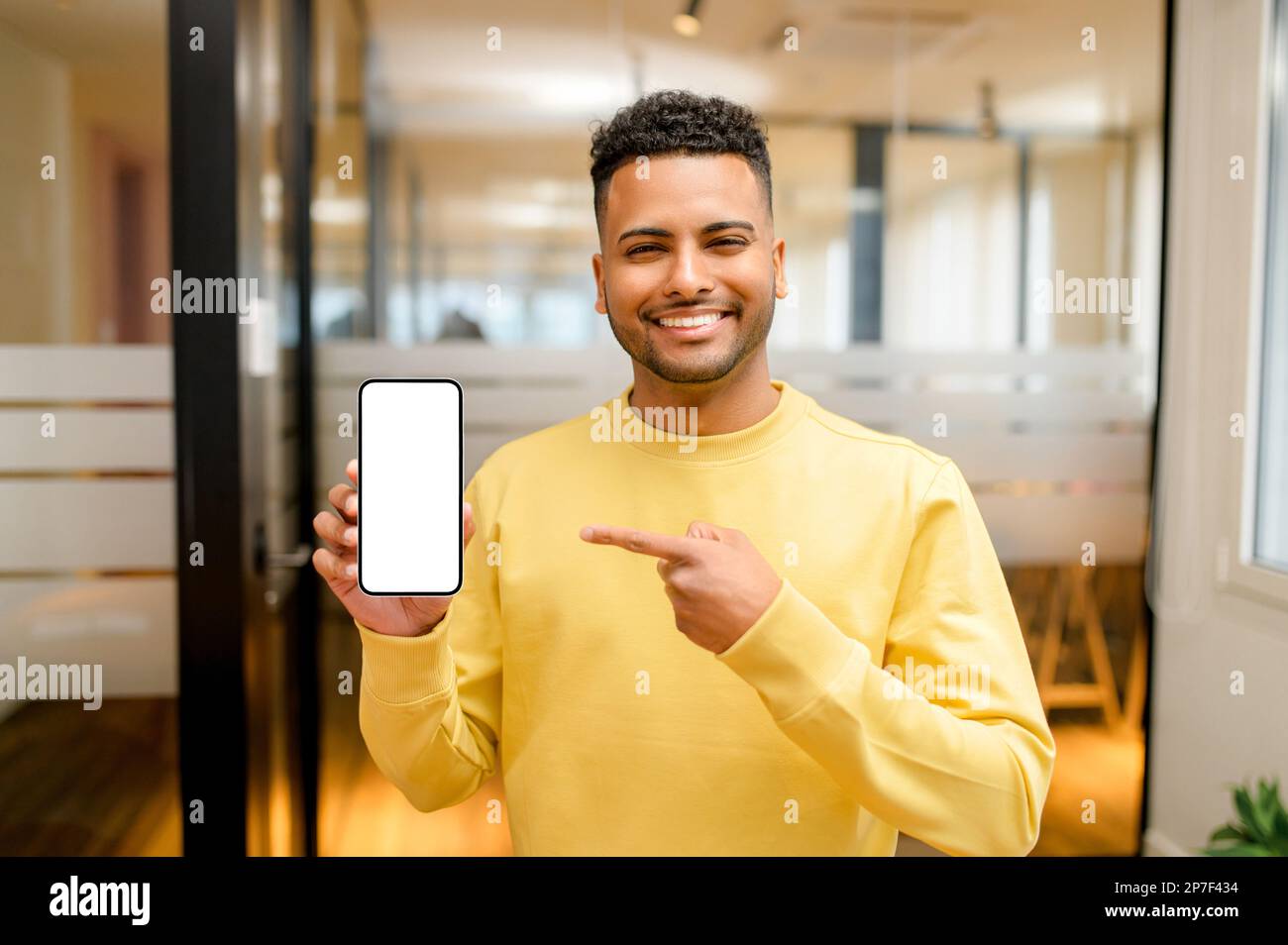 Positive smiling indian man freelancer showing smartphone with empty ...
