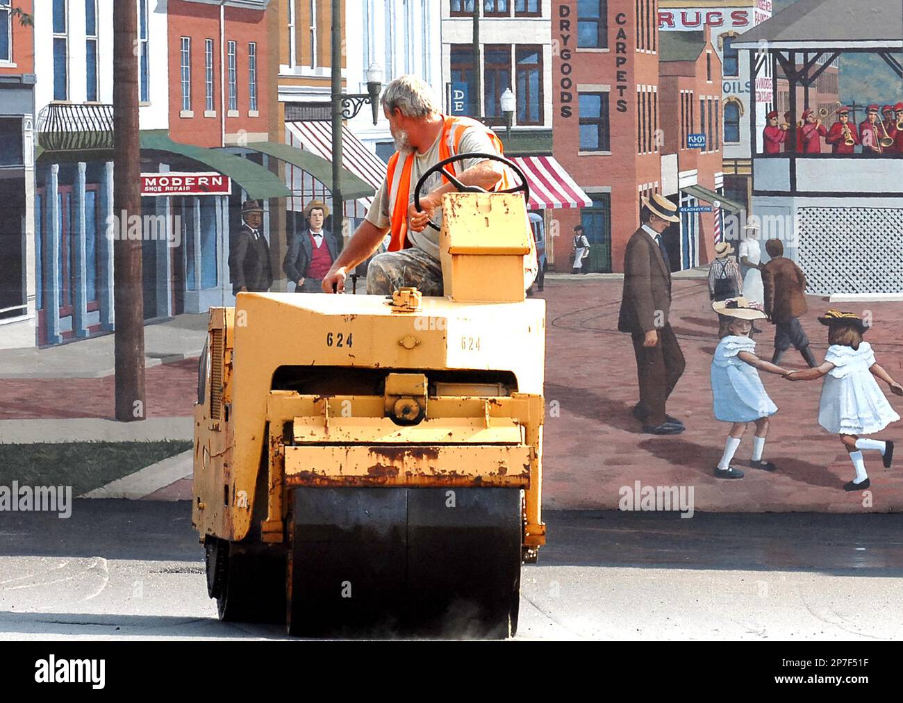 Workers pave a parking lot near a floodwall mural in downtown Maysville ...