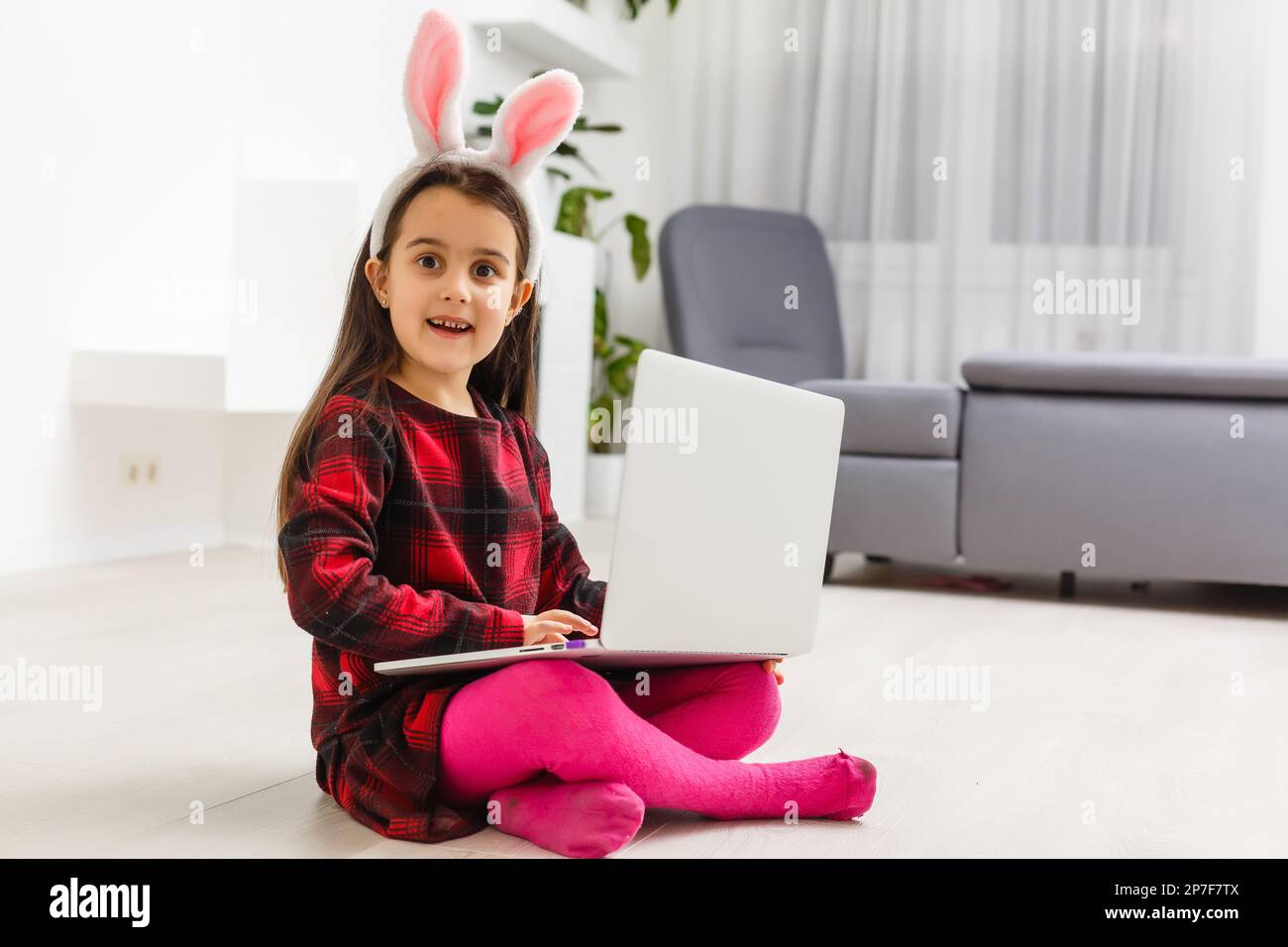 Little girl with her bunny using computer together preparing for easter ...