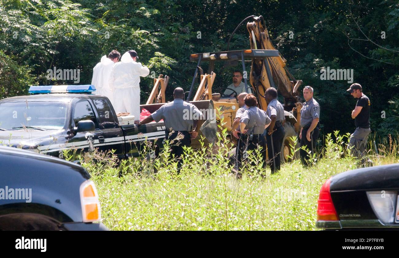 Law enforcement officials load a cement-filled garbage can onto the ...