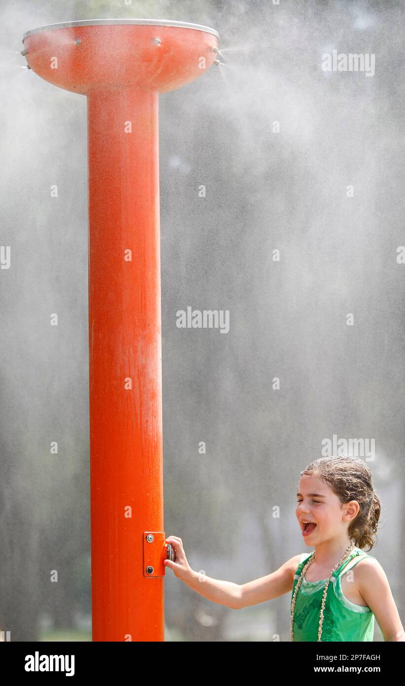 Emma Mitchell pushes a button to start a water mister at Trinity Park ...