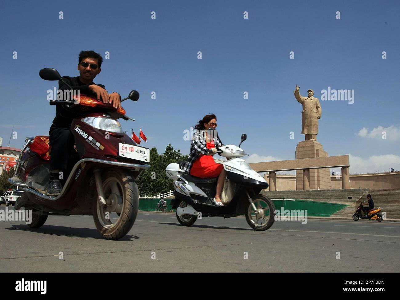 Local residents ride motorbikes past the statue of late Chinese leader ...