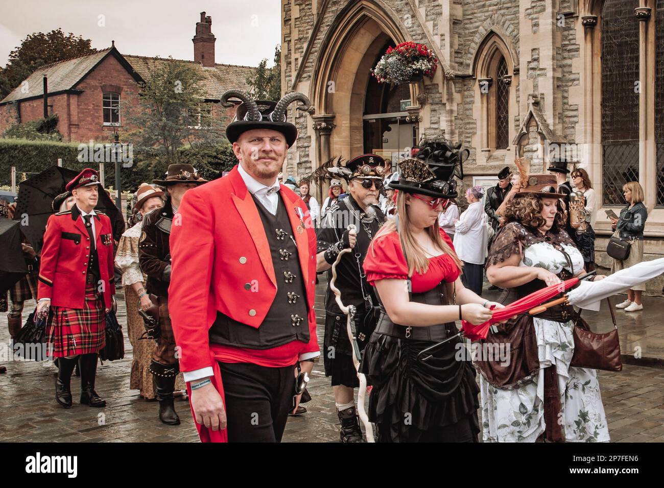 A group of steampunks walking along a street. A male steampunk with a ...