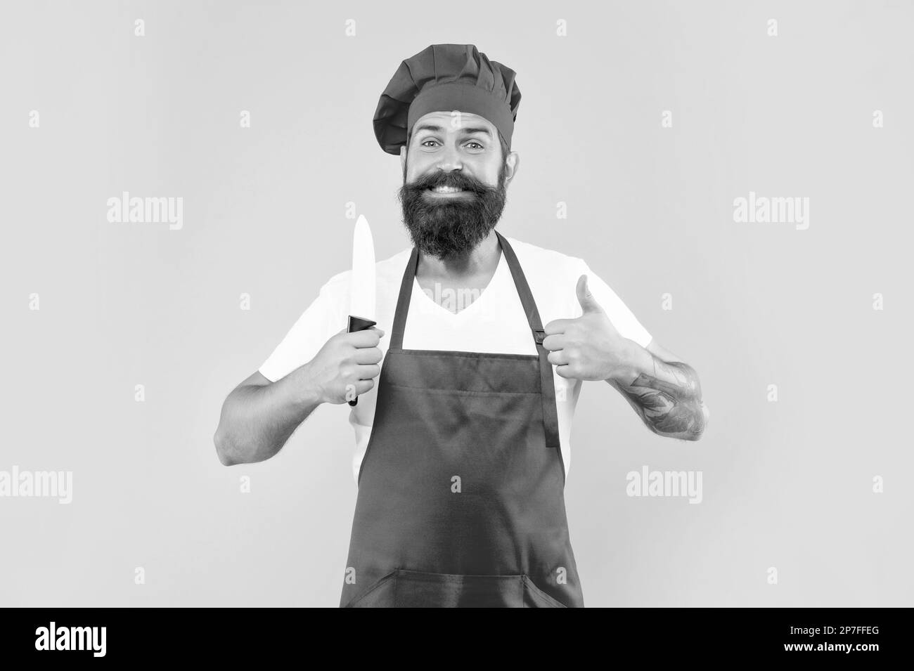 Happy man in red apron and toque giving thumb holding chefs knife ...