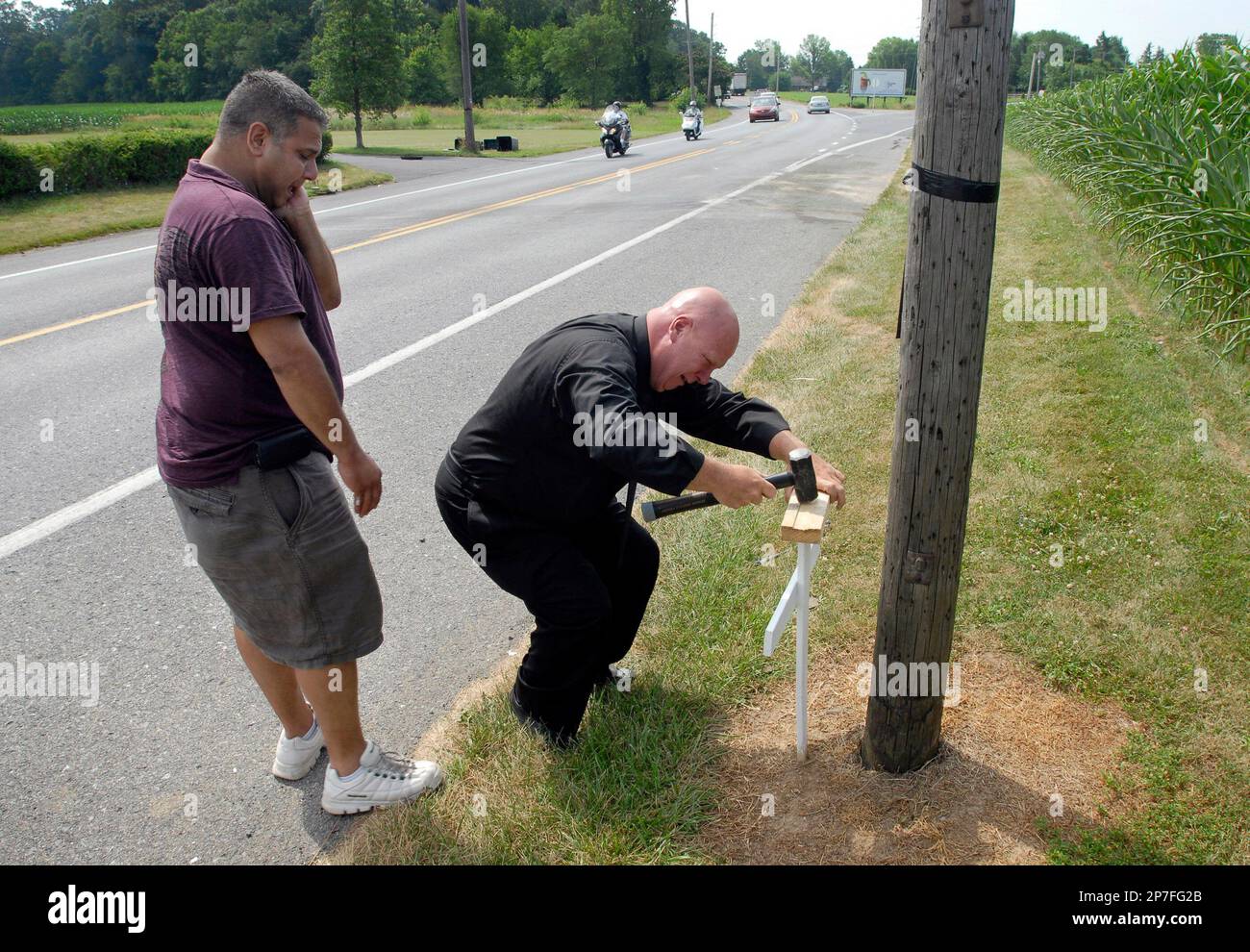 Gregg Specht hammers a white cross in the grass next to Pennsylvania ...