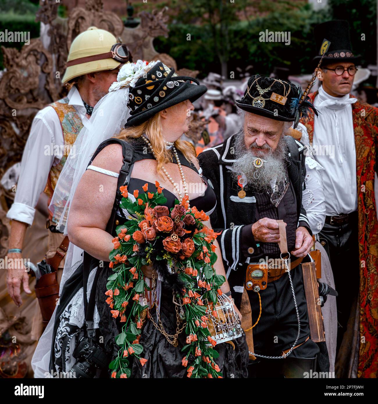 A group of steampunks walking in procession along a street. The woman ...