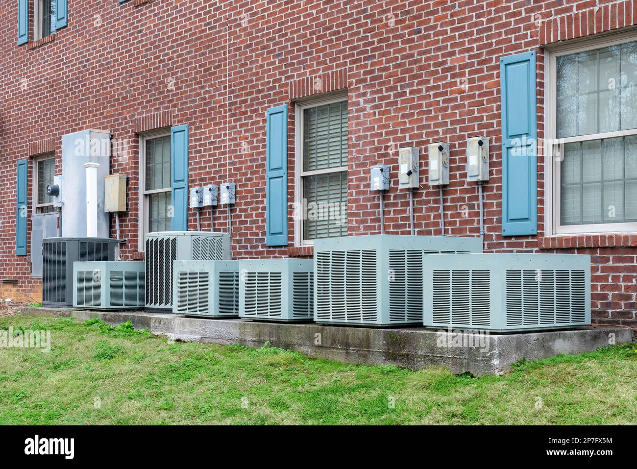 Horizontal shot of a row of various air conditioners attached to ...