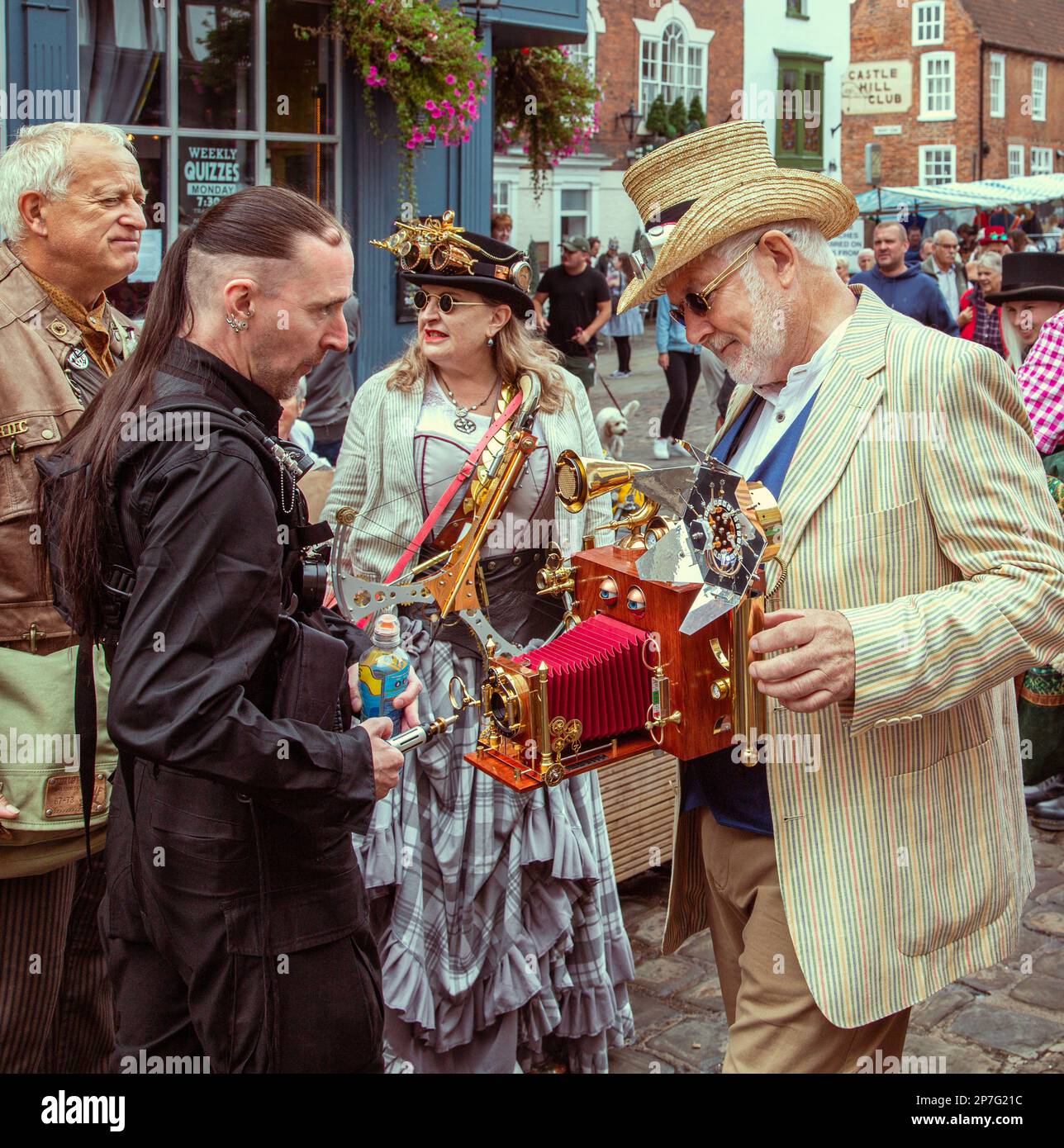 A steampunk photographer showing off his camera to a friend at a ...