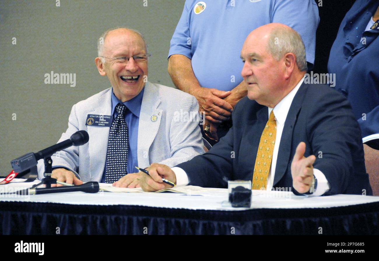 Dr. Don Thomas, left, laughs as Governor Sonny Perdue signs into law ...
