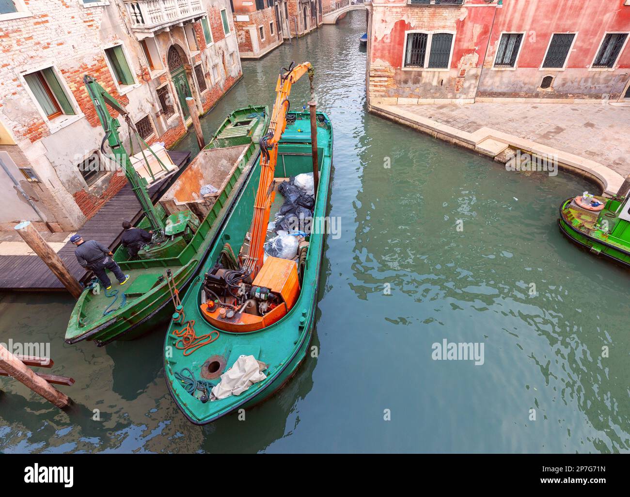 A large green self-propelled garbage collection barge in a Venetian ...