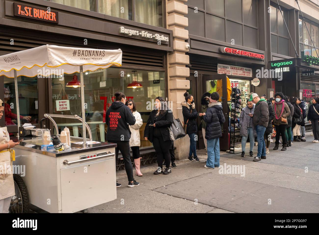 Customers queue for a free burger promotion at the grand opening of 7th ...