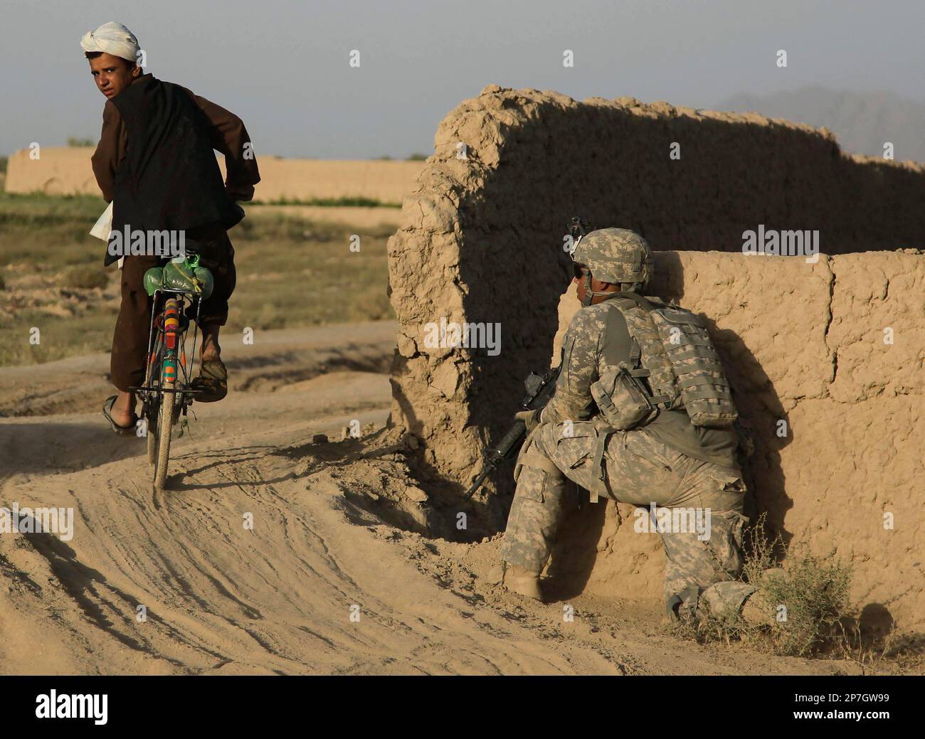 A teenage Afghan boy looks back as he passes U.S. Army Pvt. Deonte ...