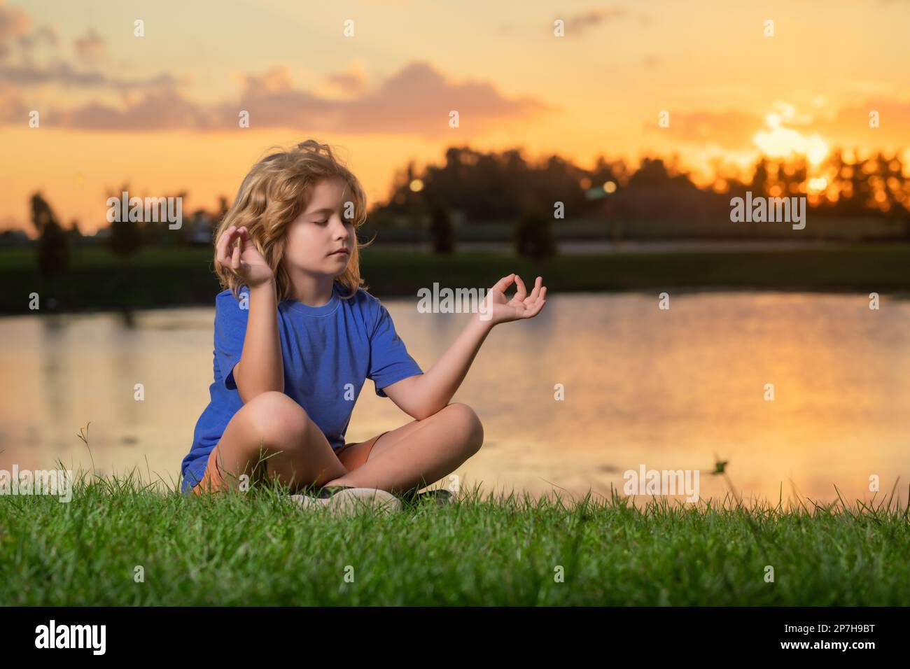 Kid practices yoga and meditates in the lotus position near lake Stock ...