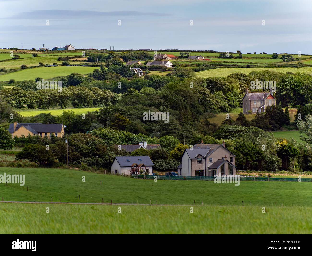 A European village among green fields, trees. Farmhouses in Ireland ...