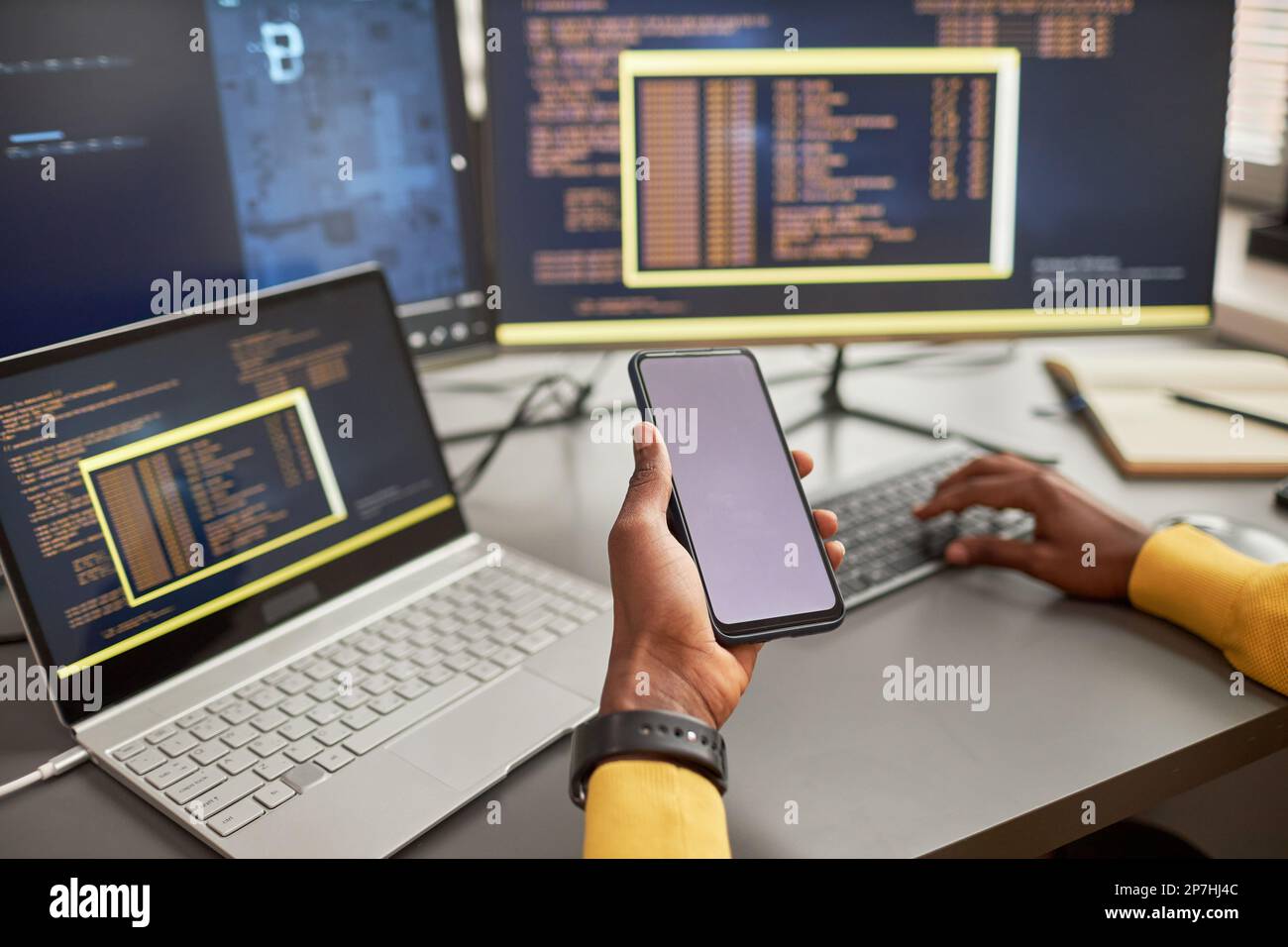 Close up of unrecognizable black man holding smartphone and writing code in IT development ...