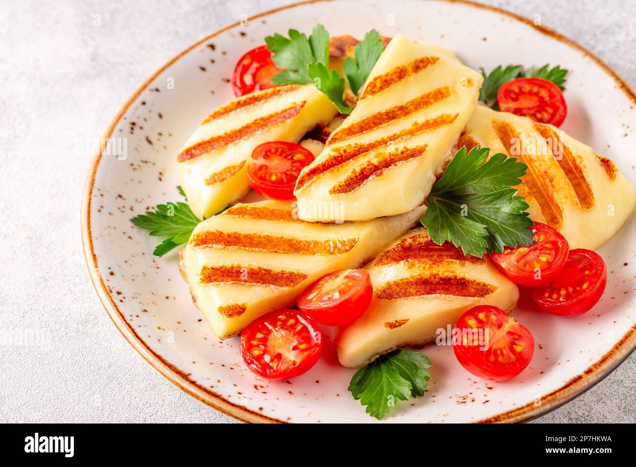 Grilled halloumi cheese served with tomatoes and parsley Stock Photo ...