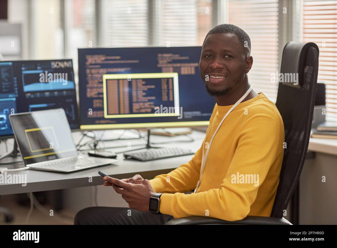 Portrait of smiling black man looking at camera while sitting at ...