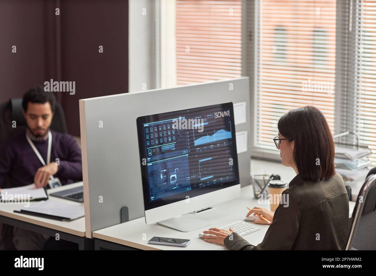 High angle view of two office workers at desk with partition wall ...
