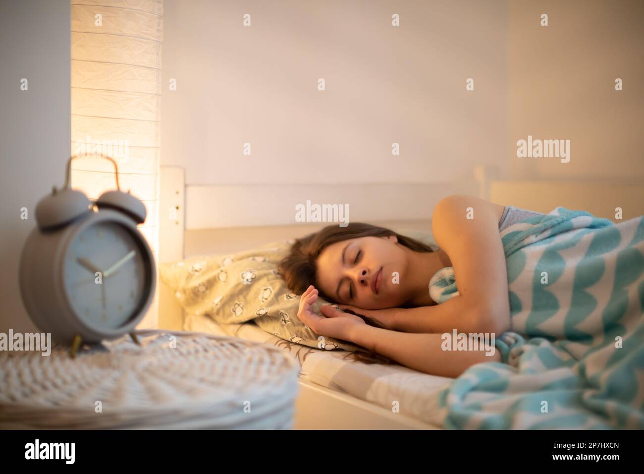 A young woman is lying on a bed in her bedroom, her eyes closed Stock ...