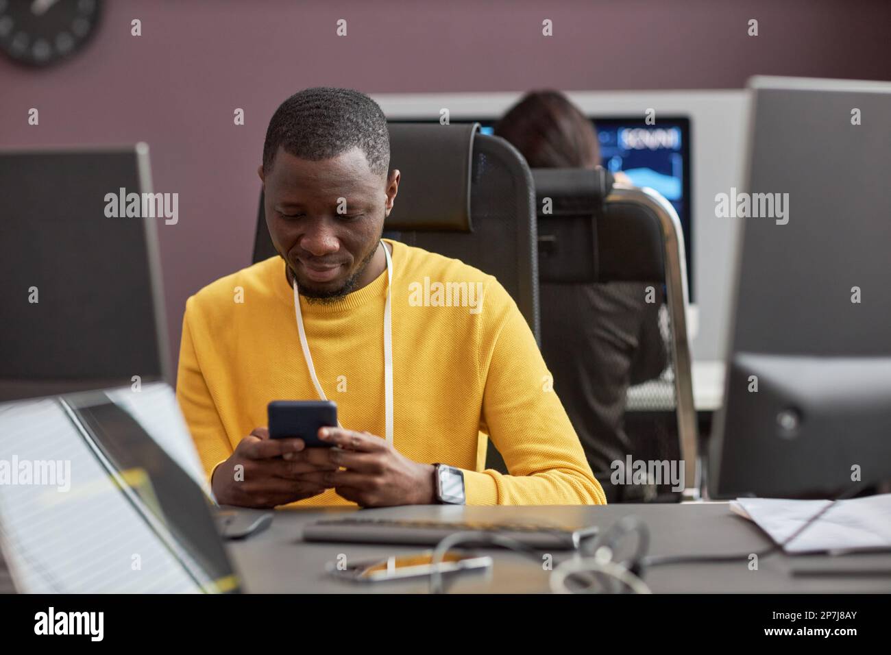 Portrait of black software developer using smartphone at office desk ...