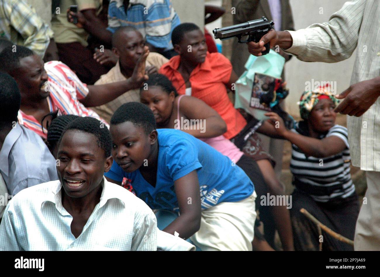 A Ugandan security personnel in plain clothes points a gun at rioters ...