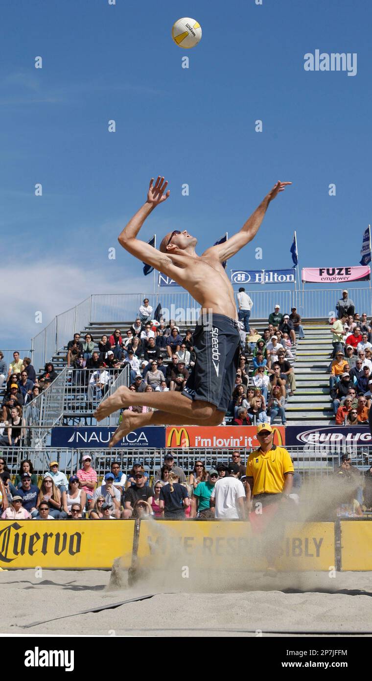 Phil Dalhausser, catches some air as he sets up a serve as Todd Rogers ...