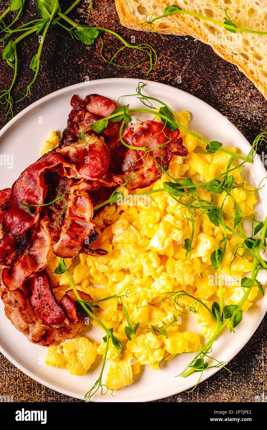 Traditional breakfast scrambled eggs with fried bacon. Top view Stock Photo - Alamy