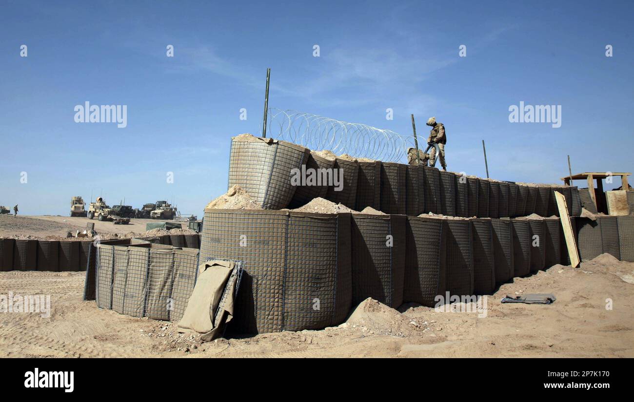 U.S. Marines with NATO forces put barbed wires on top of the protective ...