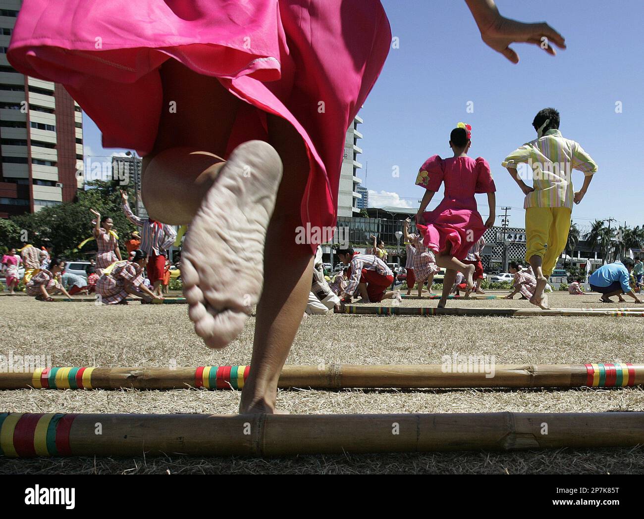 Filipinos in colorful costumes demonstrate the native "Tinikling ...