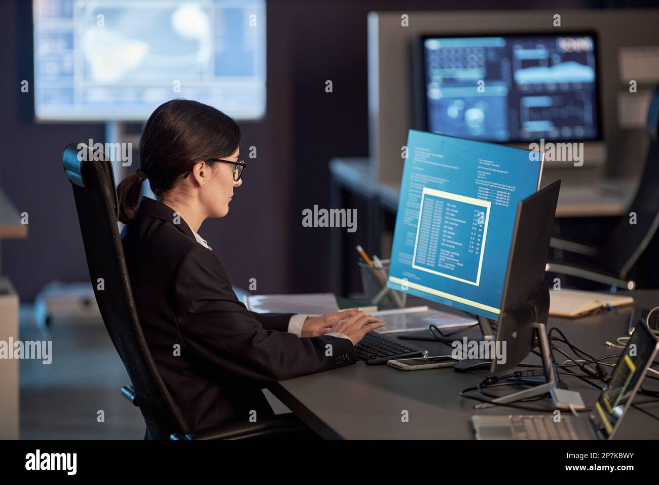 Side view portrait of female IT developer using computer at workplace ...