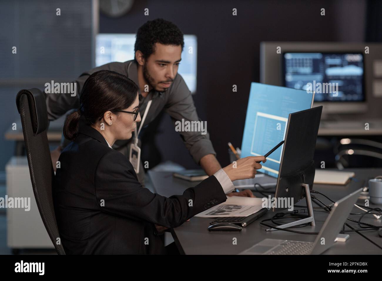 Side view portrait of two people pointing at computer screen while ...
