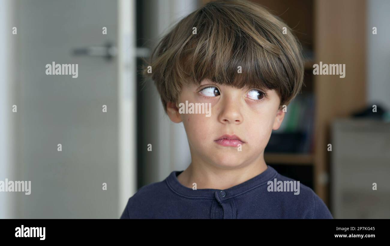 Portrait of one pensive young boy looking sideways thinking. Close up face of a child standing ...