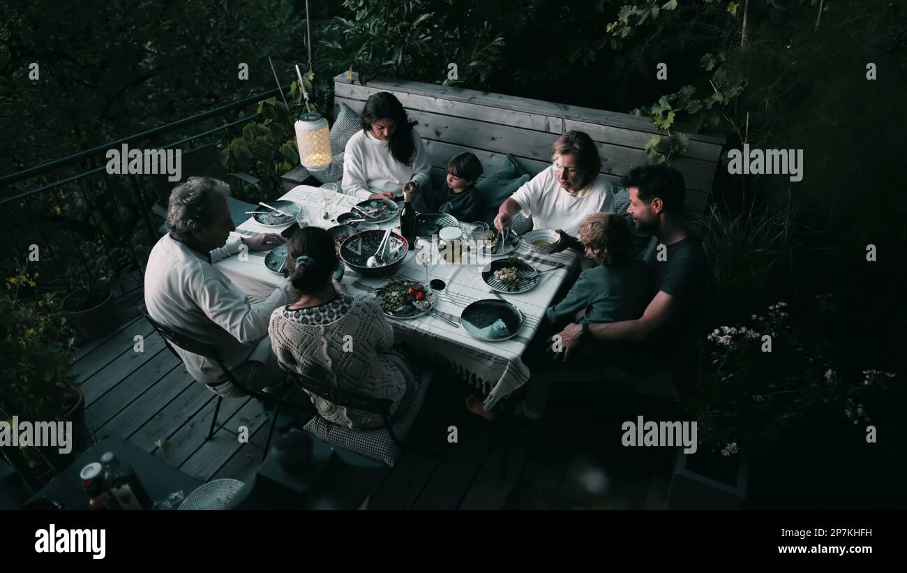 Parents and children seated at dinner table eating meal together. From ...