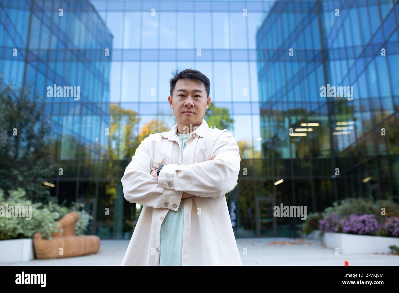 Portrait of a serious young handsome successful male Asian programmer ...