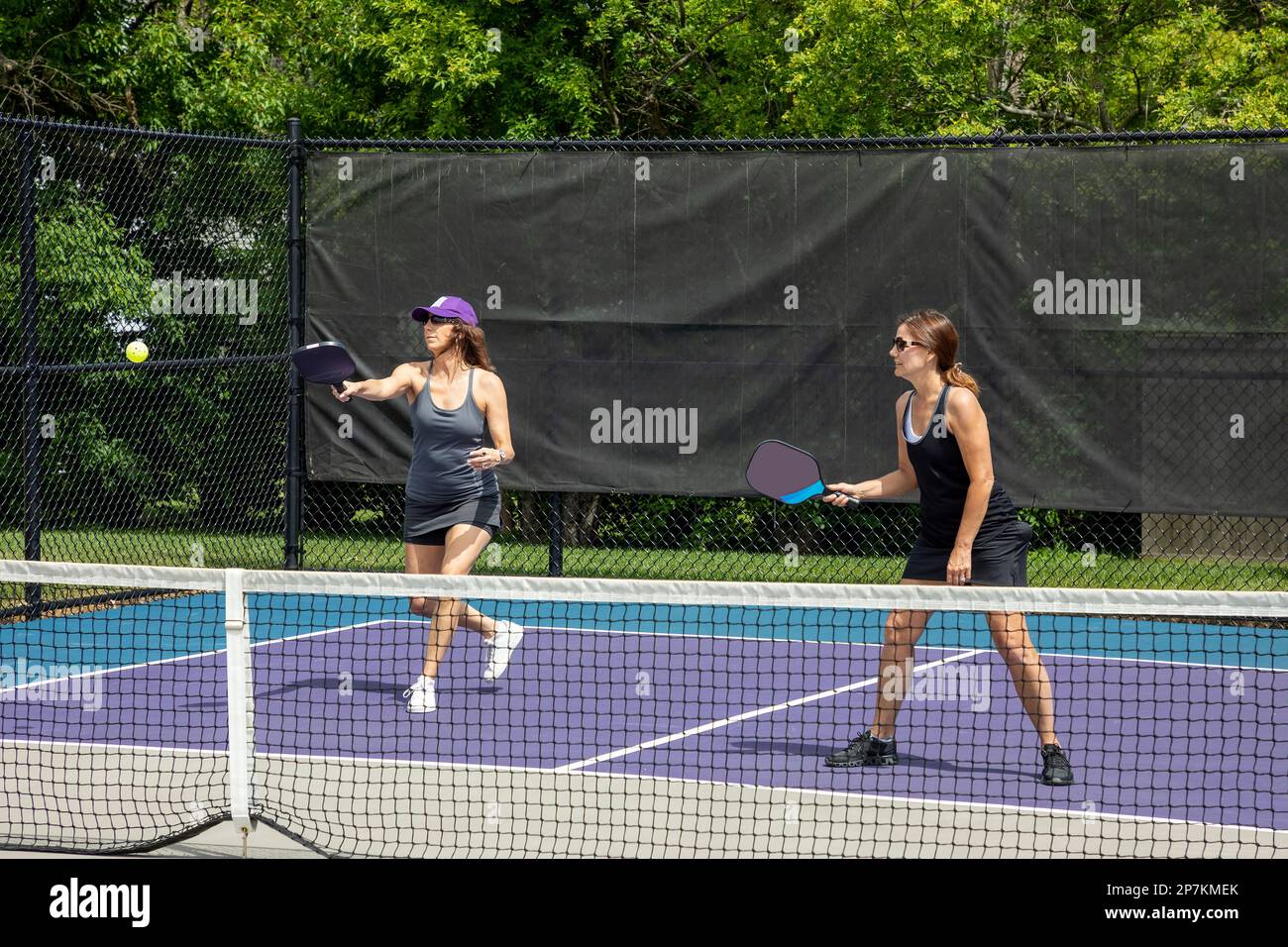 Two pickleball players in action on a suburban pickleball court during ...
