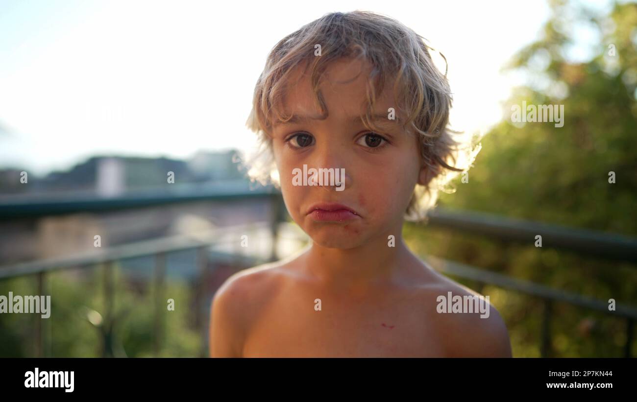 Portrait of a young boy with sad expression. Sulky emotion of a little male kid standing ...