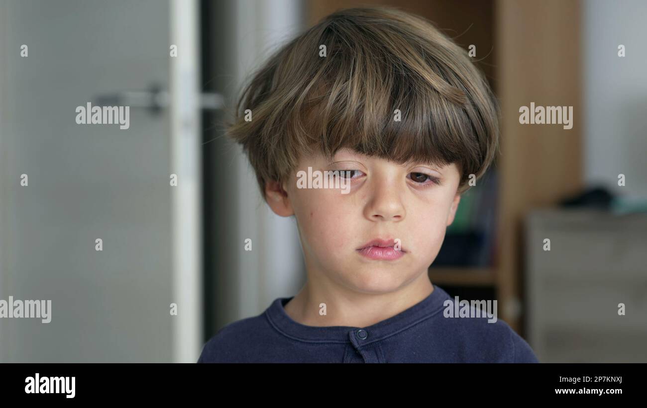 Portrait of one pensive young boy looking sideways thinking. Close up face of a child standing ...