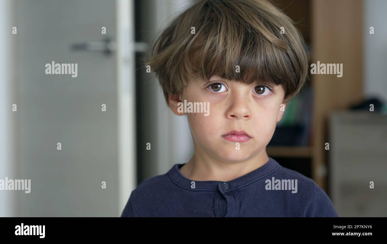 Portrait of one pensive young boy looking sideways thinking. Close up face of a child standing ...
