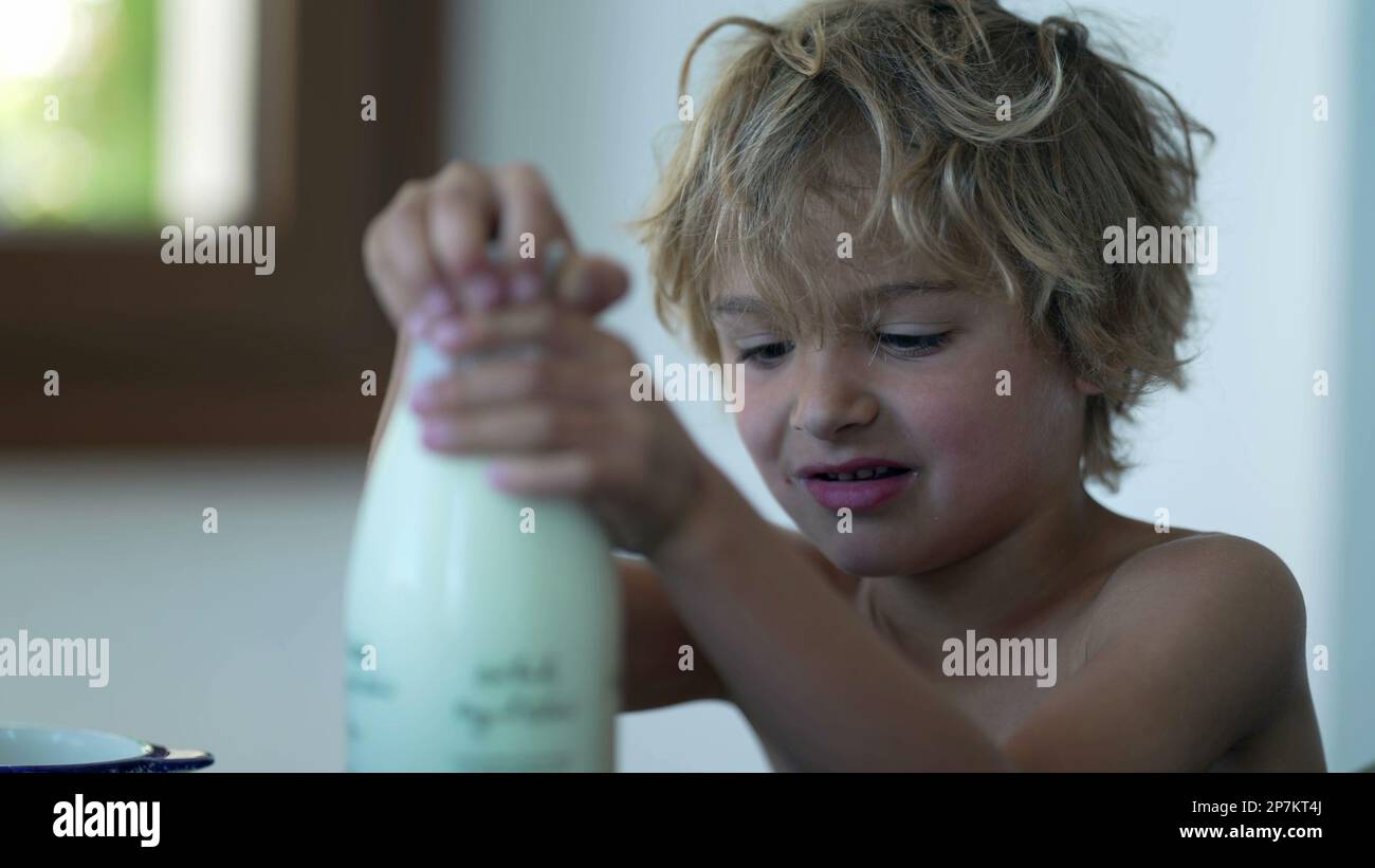 One young boy trying to open bottle of milk. Kid unable to free glass ...