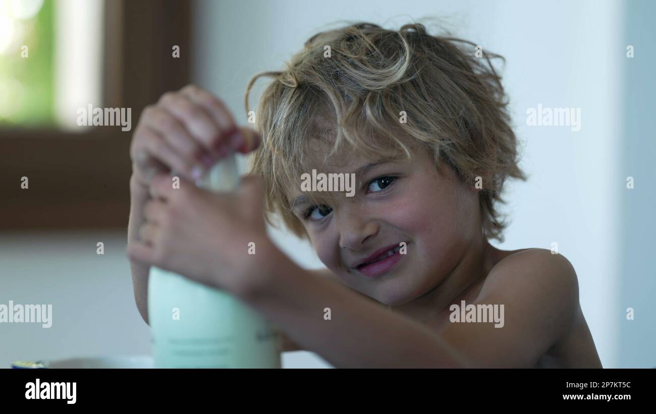 One young boy trying to open bottle of milk. Kid unable to free glass ...